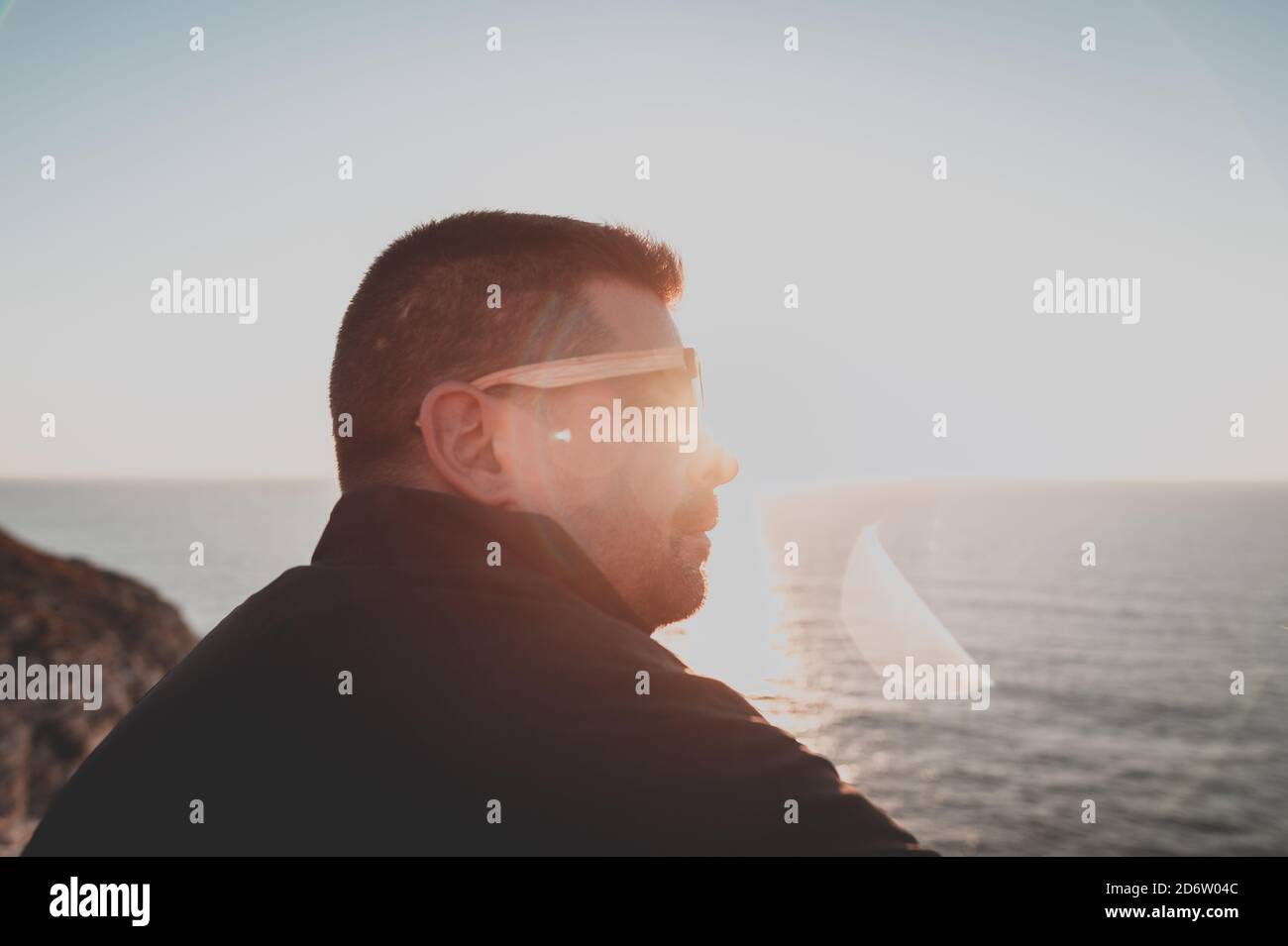 Young man looking out over ocean at sunset in Portugal in summer Stock ...