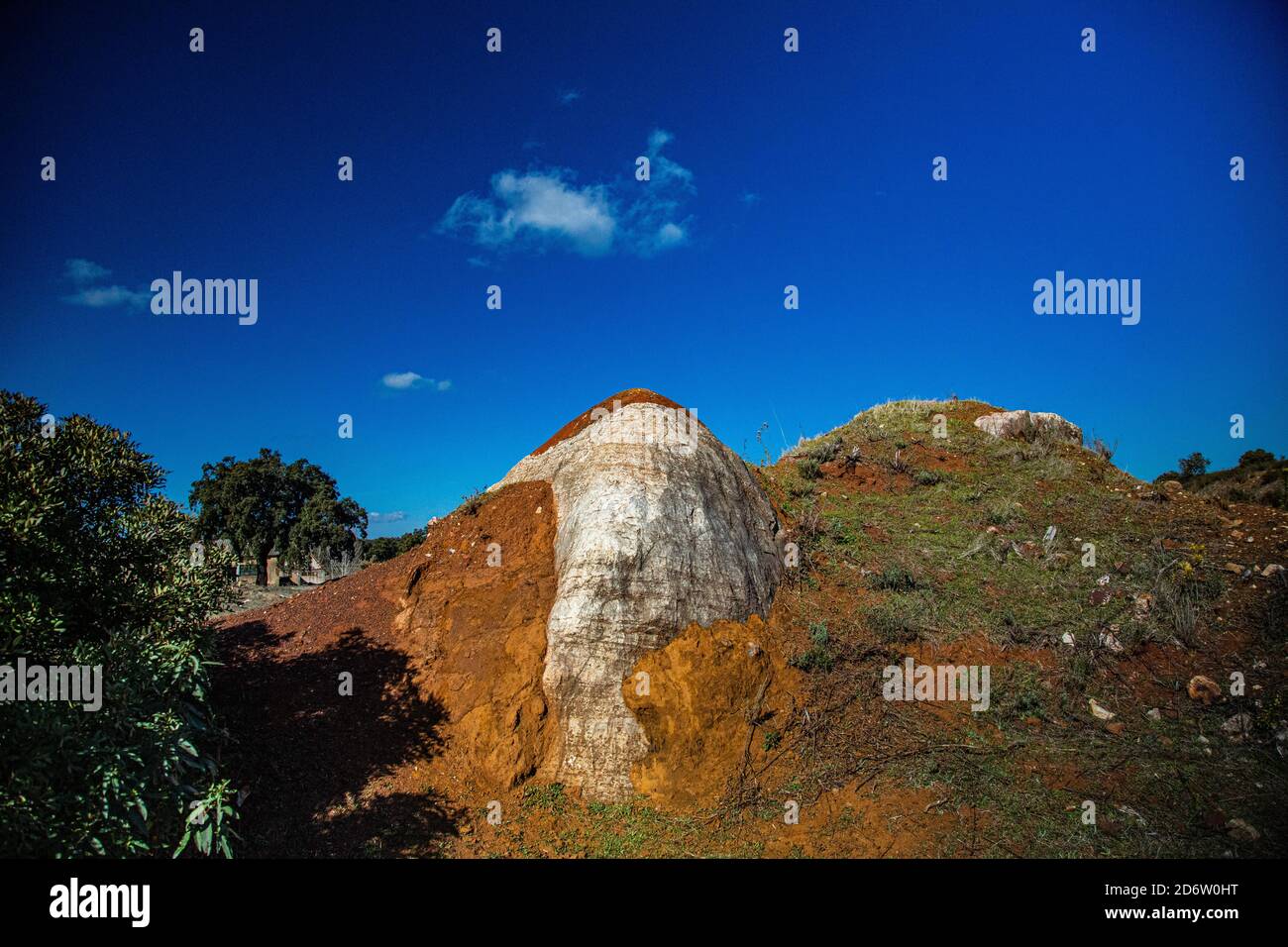 Volcanic rock ledge on red earth and trees around Stock Photo - Alamy