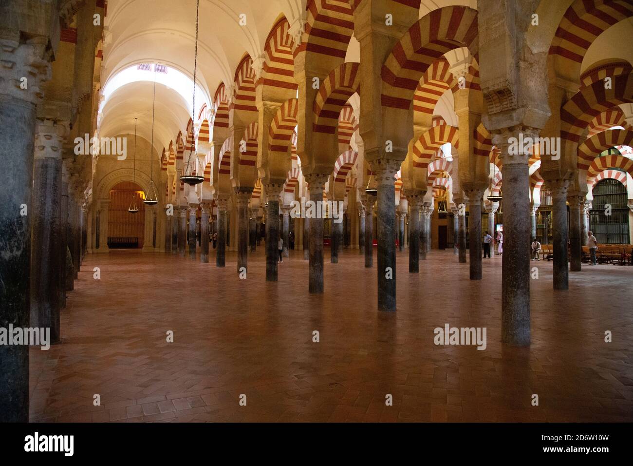 Reddish tiled floor in corridor with columns and double arches in mosq ...