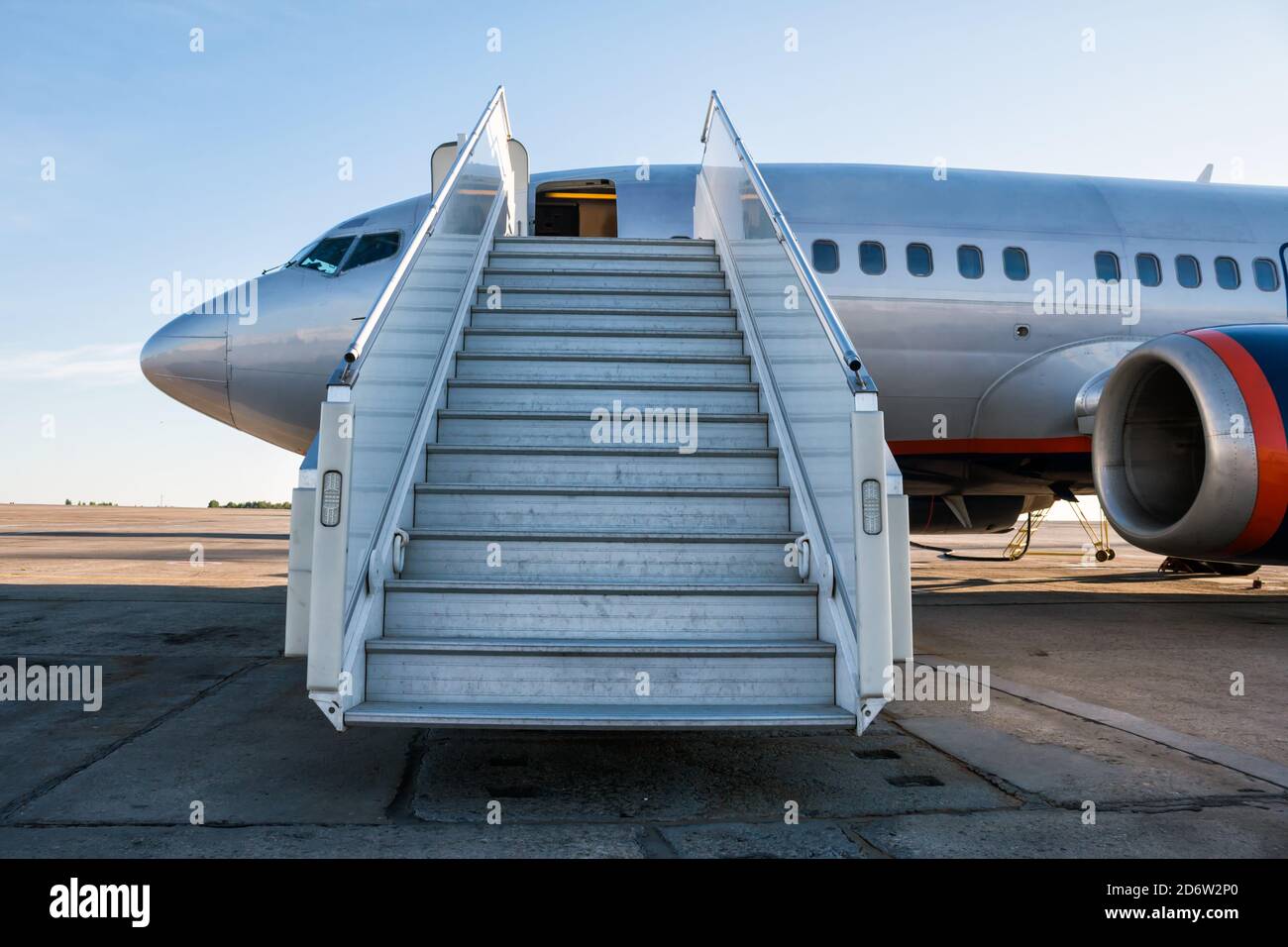 Passenger aircraft with a boarding ramp on the airport apron Stock ...