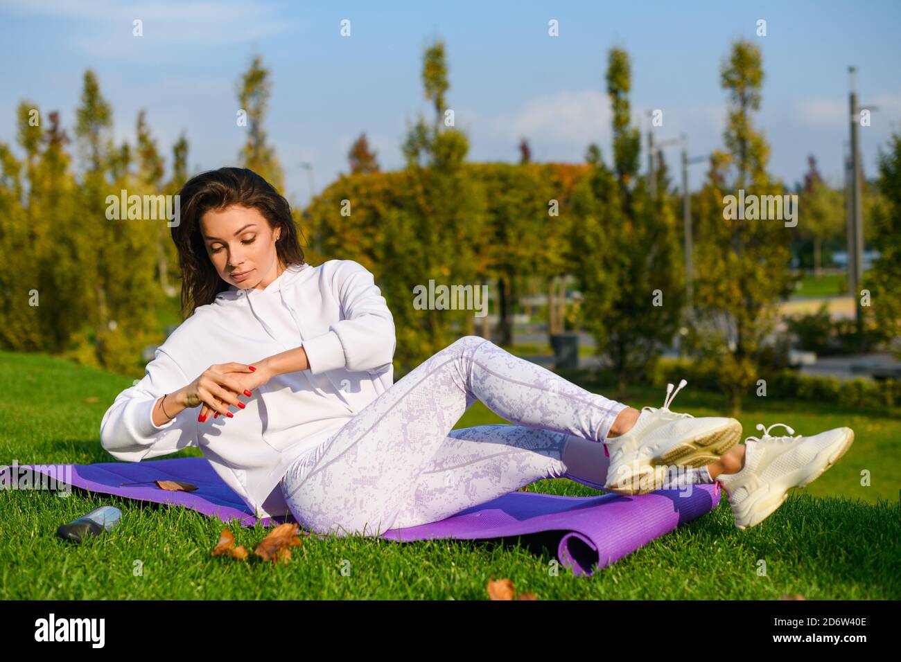 Pretty brunette sporty woman lay on mat at sunny green day and make ...