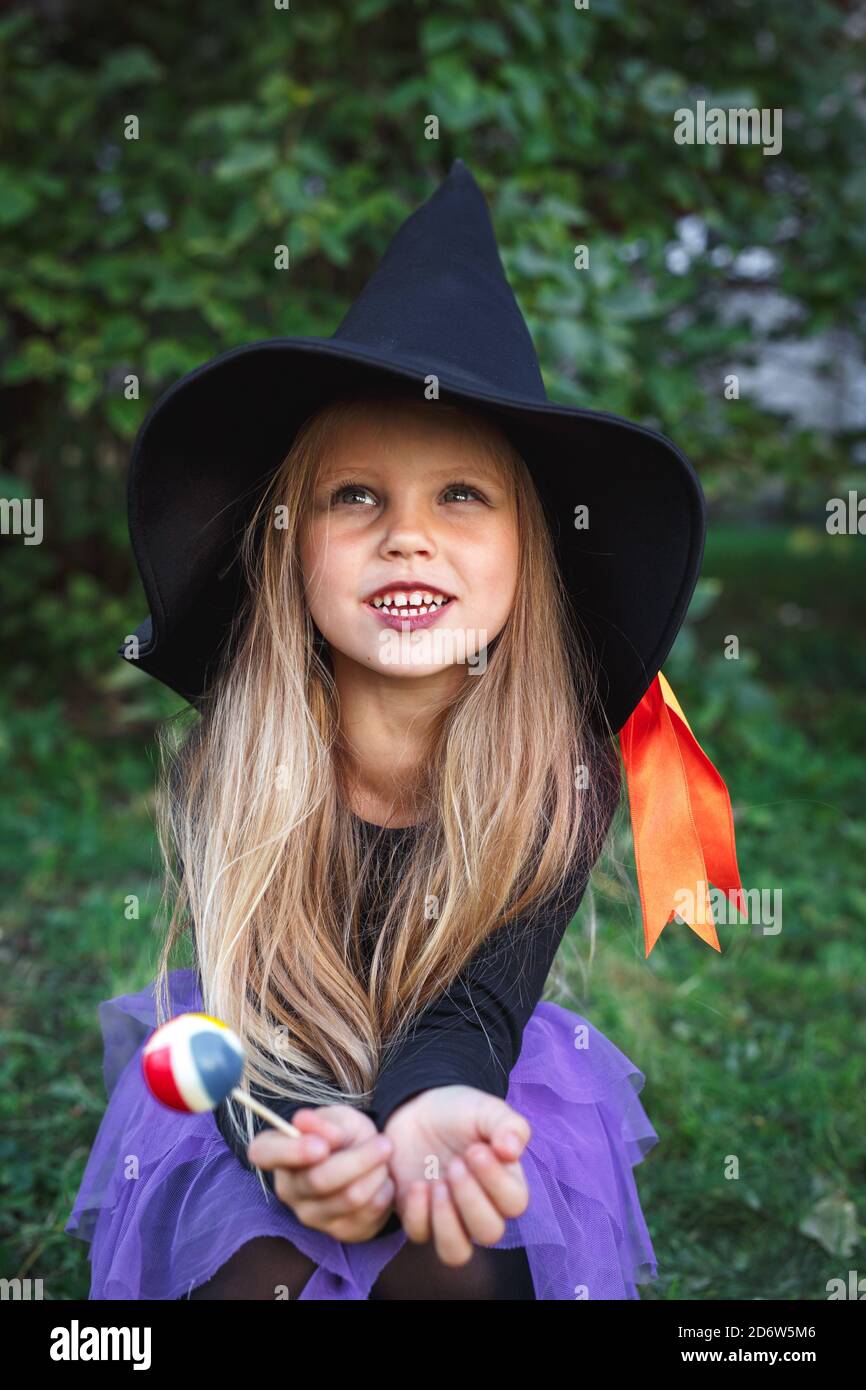 Funny little girl in witch costume eating Halloween candy outdoor Stock ...