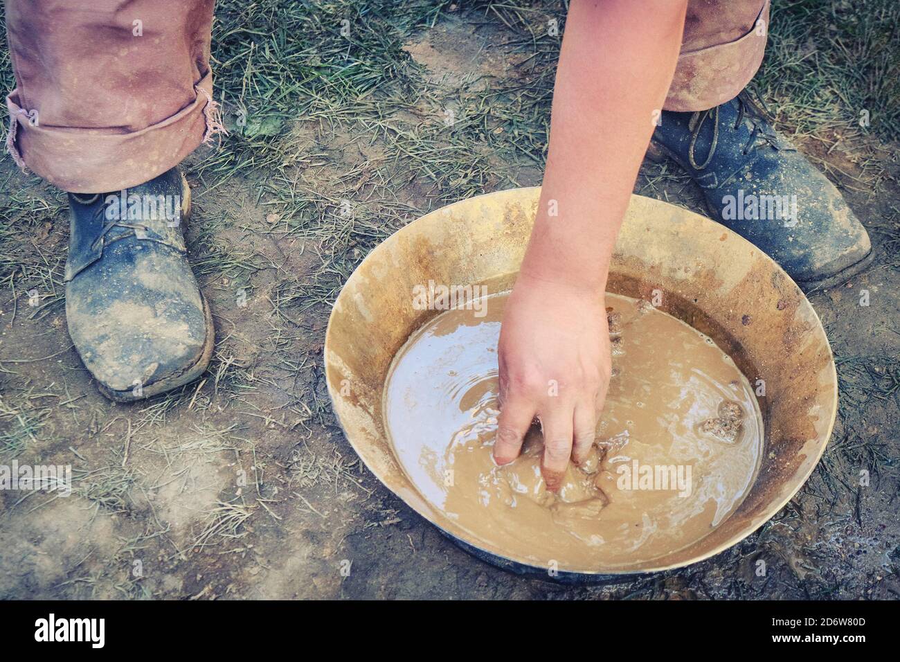 A man washes gold sand in a copper tray. Washing of gold in the tray by ...