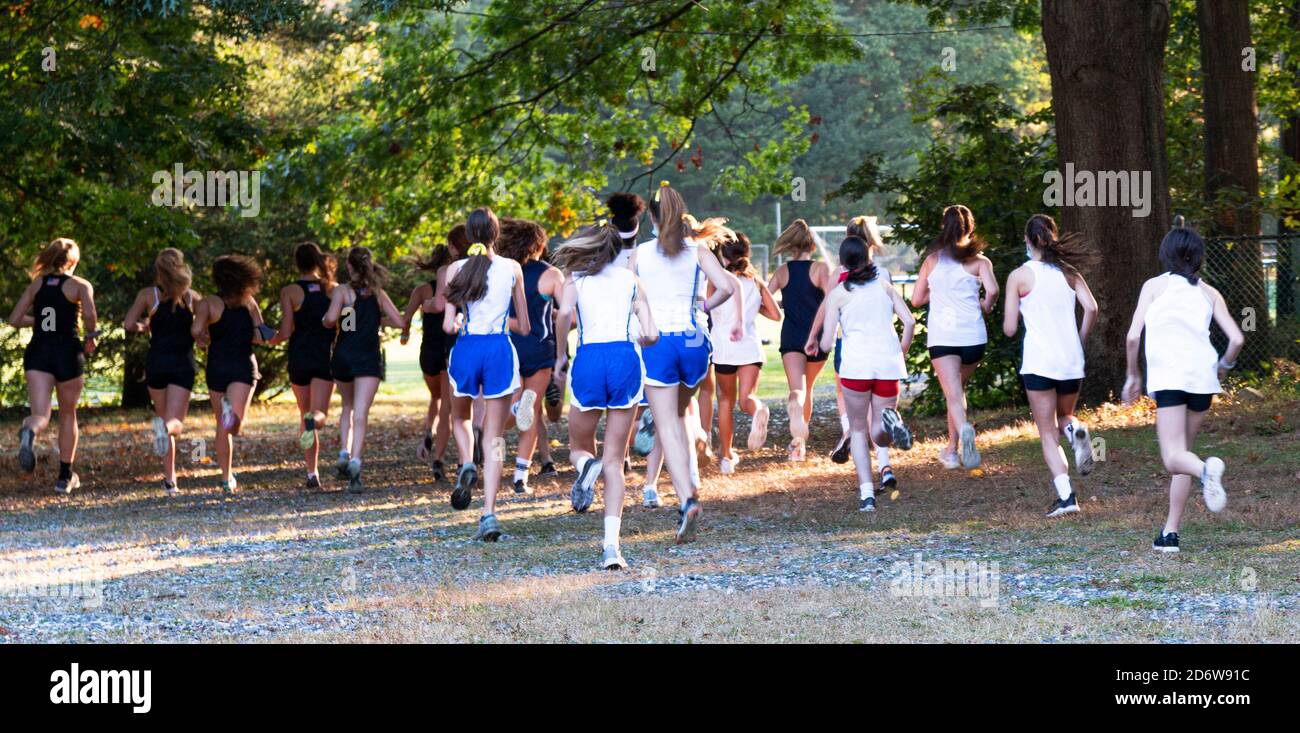 Rear view of the start of a girls running race on rocks and grass as ...