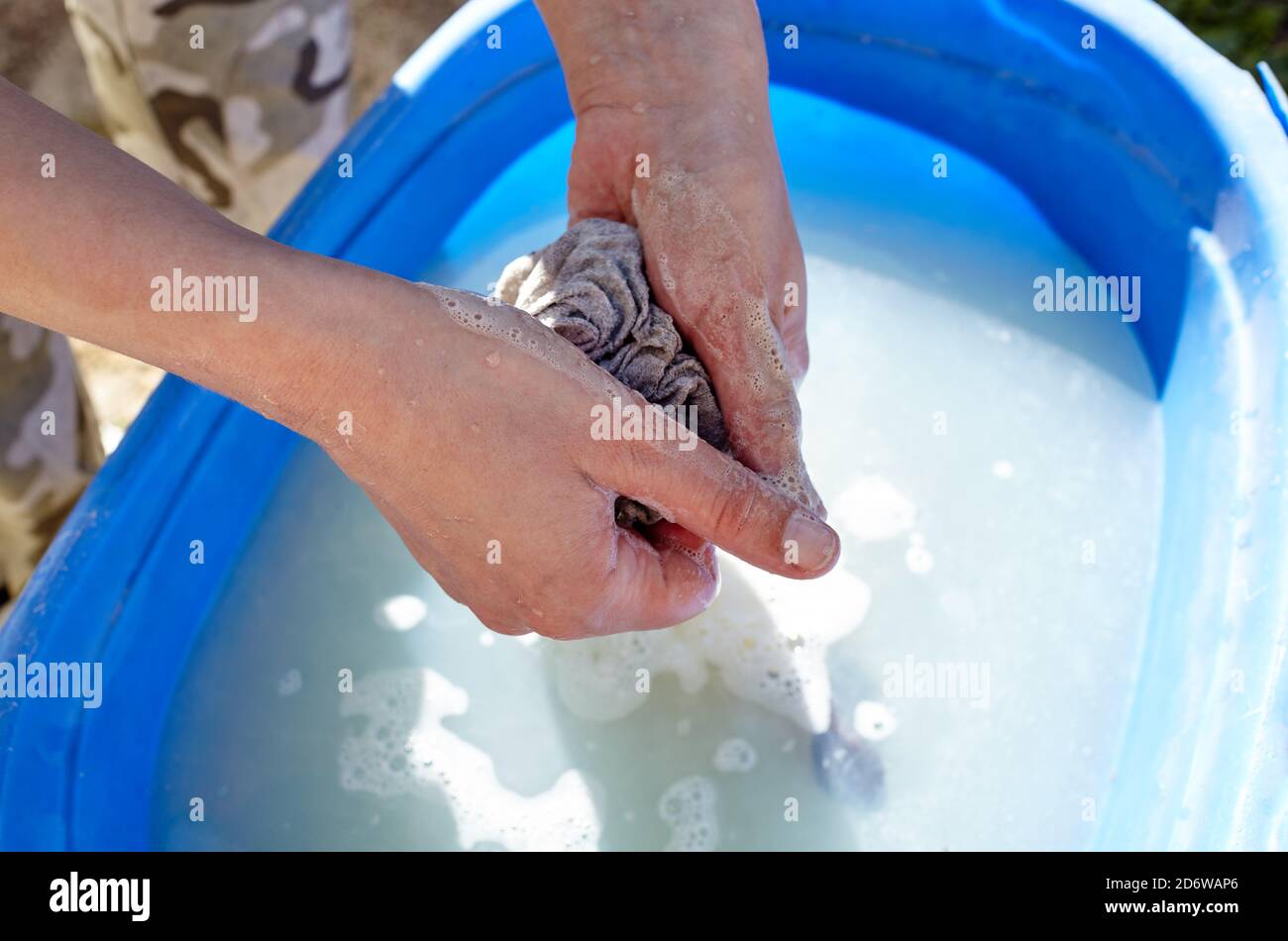 Manual hand washing. Close-up of woman hand washing laundry in blue ...