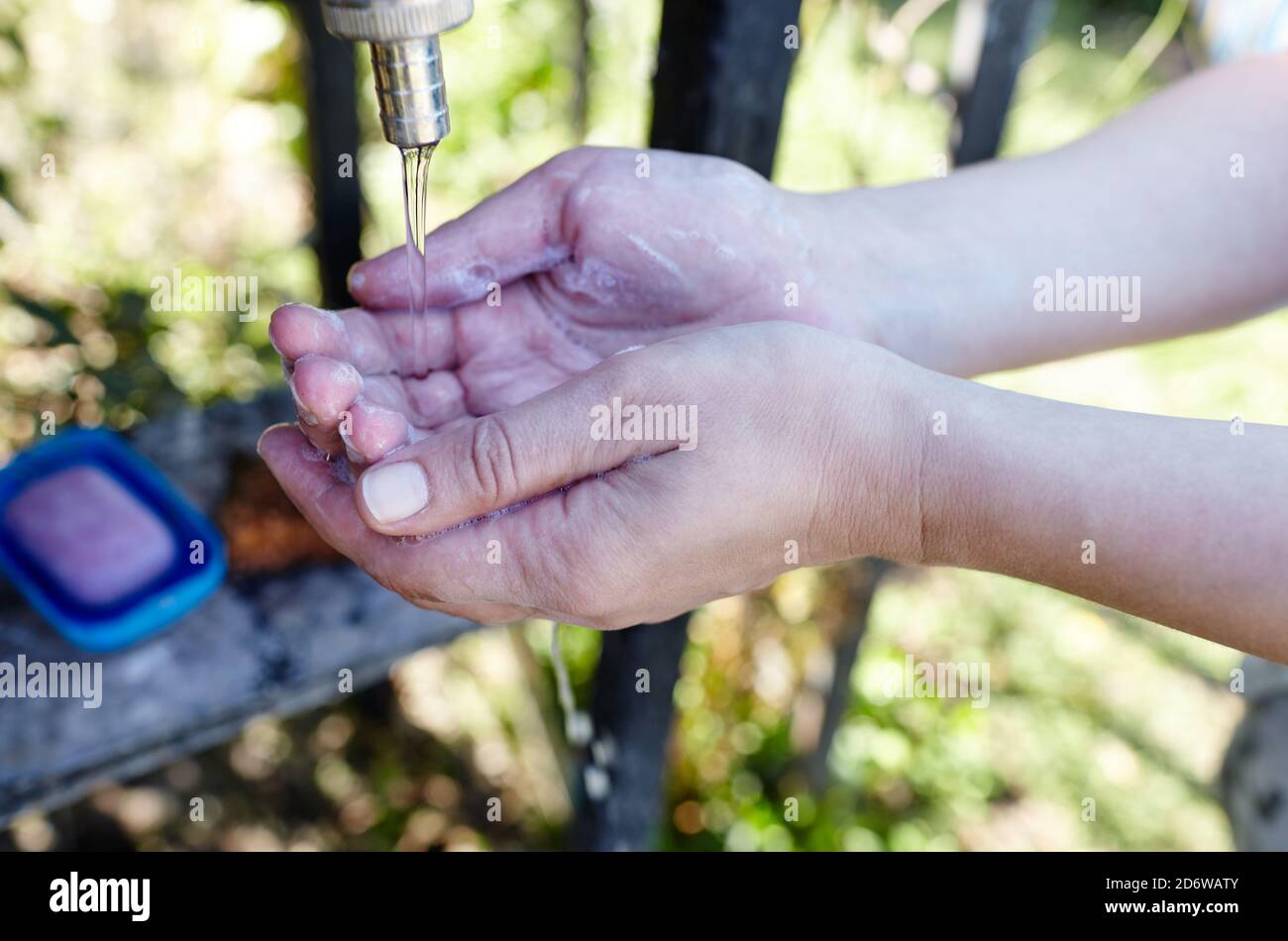 Hand washing. Woman washes her hands under the faucet in the summer in ...