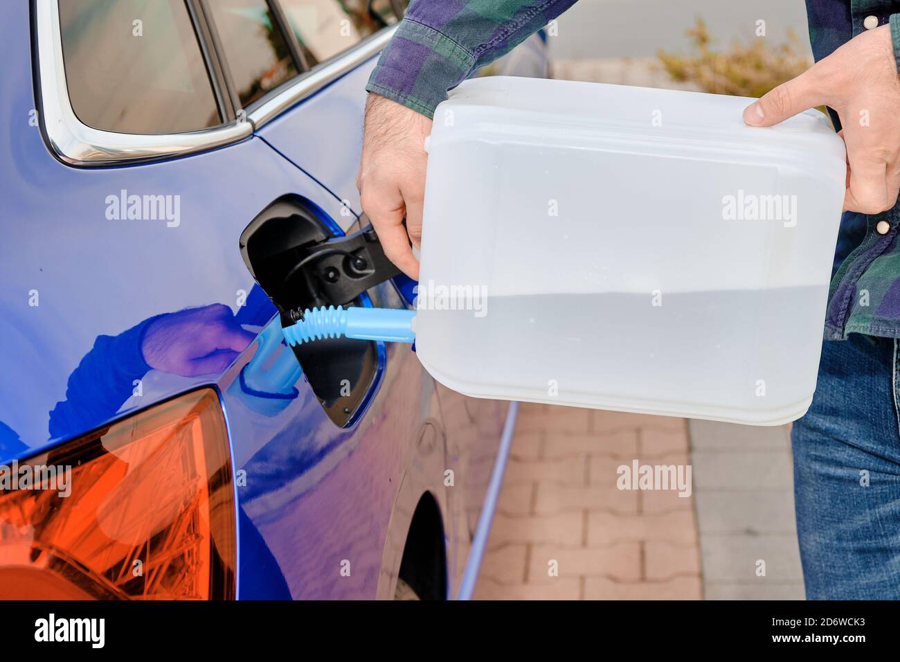 Close up man filling a diesel engine fluid from canister into the tank ...