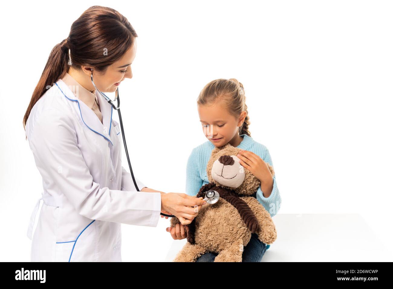 Smiling doctor examining with stethoscope soft toy near girl isolated ...