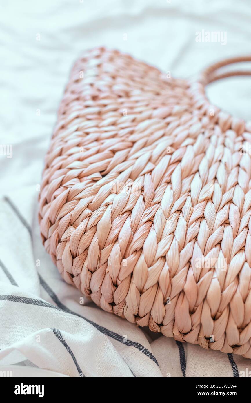 Wicker braid bag on white bed, vertical photo Stock Photo - Alamy