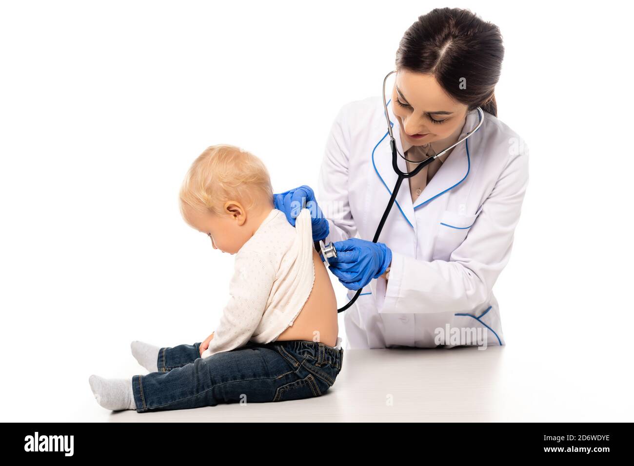 Smiling pediatrician examining back of toddler boy with stethoscope ...