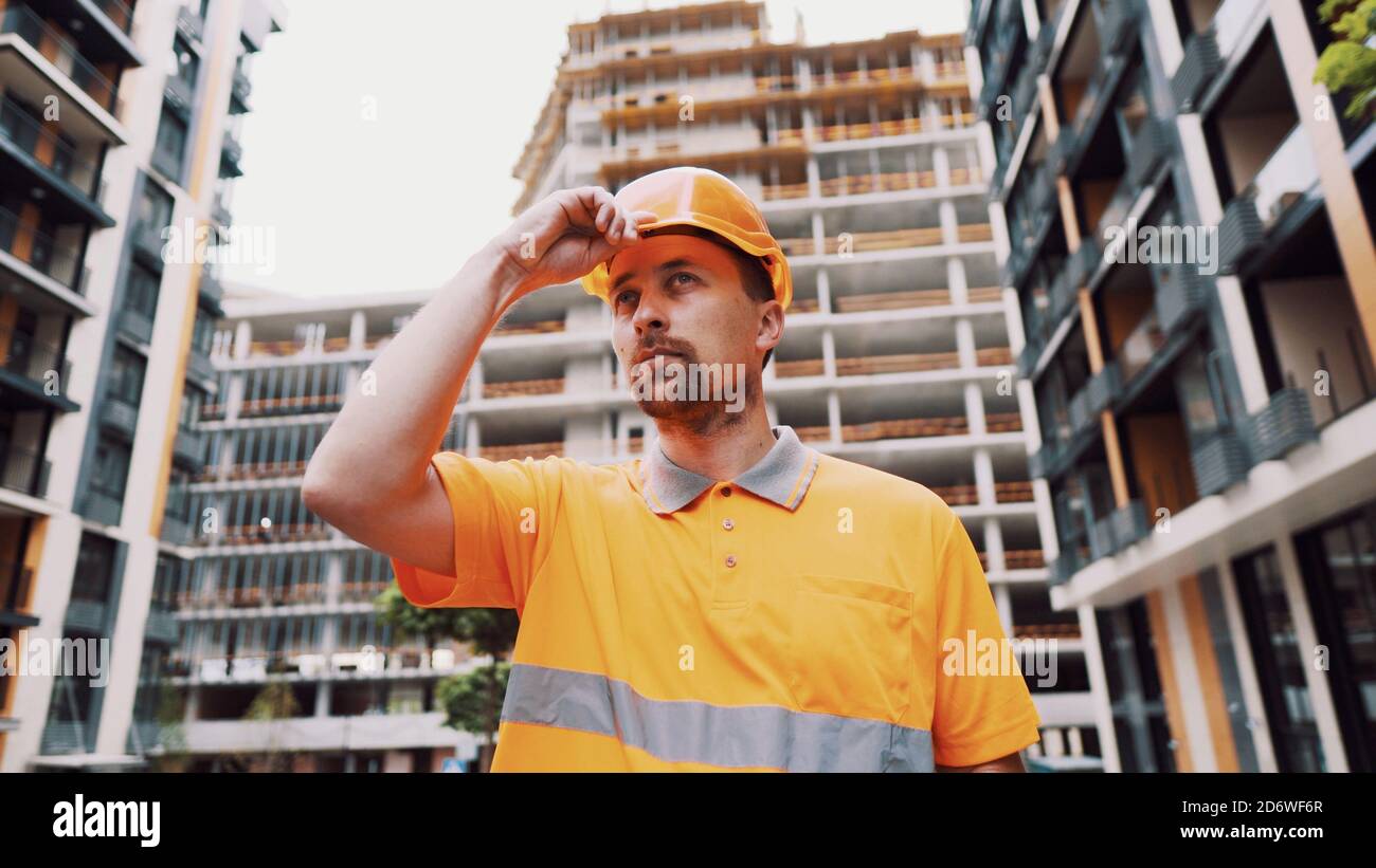 Construction worker putting on his safety gear helmet at job site ...