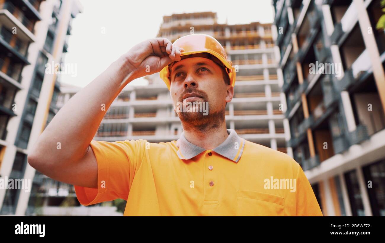 Construction worker putting on his safety gear helmet at job site ...