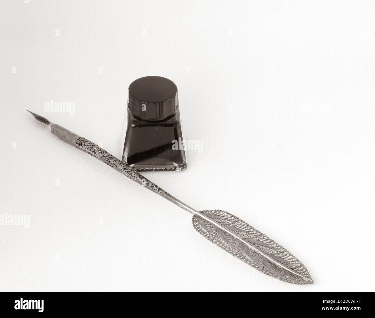 Old ink pen with metal filigreed and ink bottle isolated on white ...
