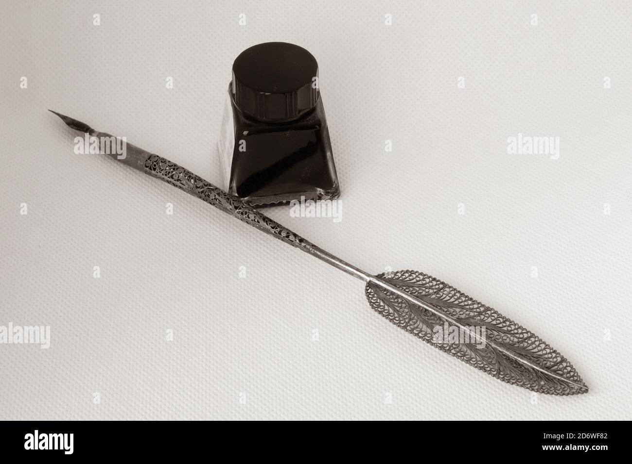 Old ink pen with metal filigreed and ink bottle isolated on white ...