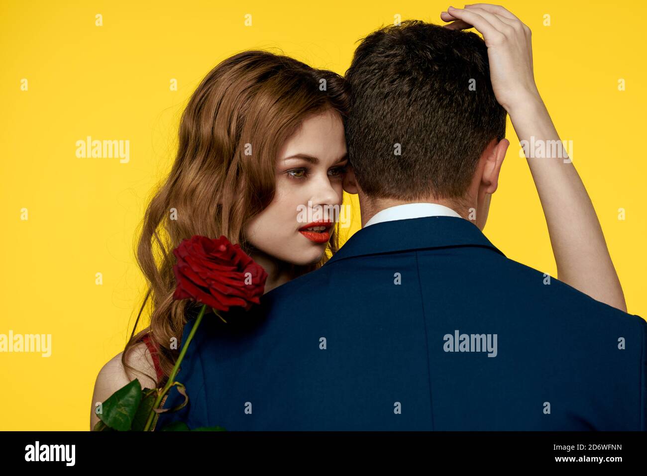 A romantic man hugs a woman in a red dress with a rose in his hand on a ...
