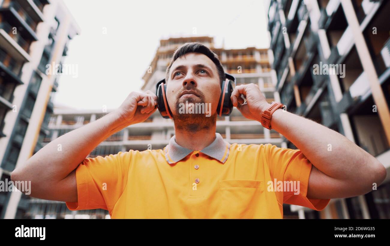 Builder covers his ears, ear muff to protect workers ears. Construction ...