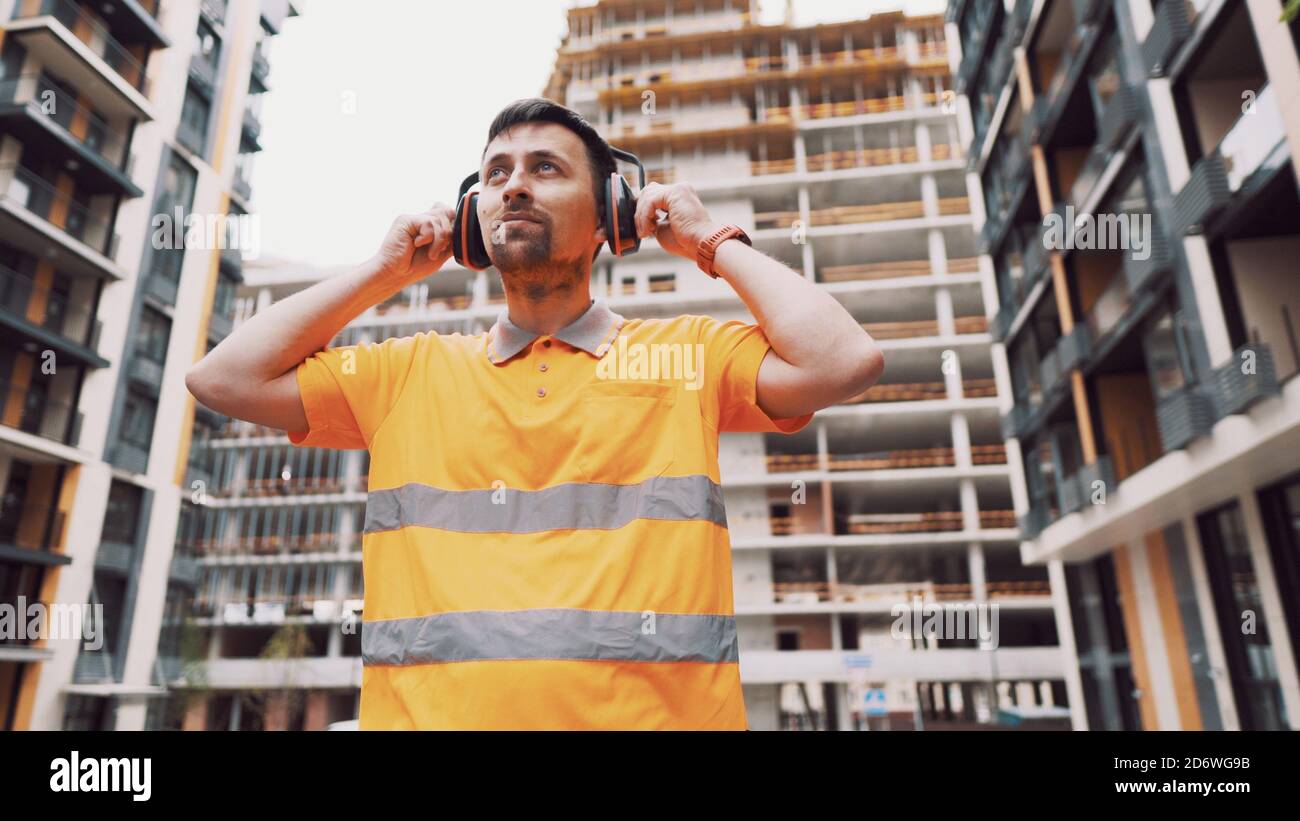 Construction worker with ear muff working at construction site. Worker ...