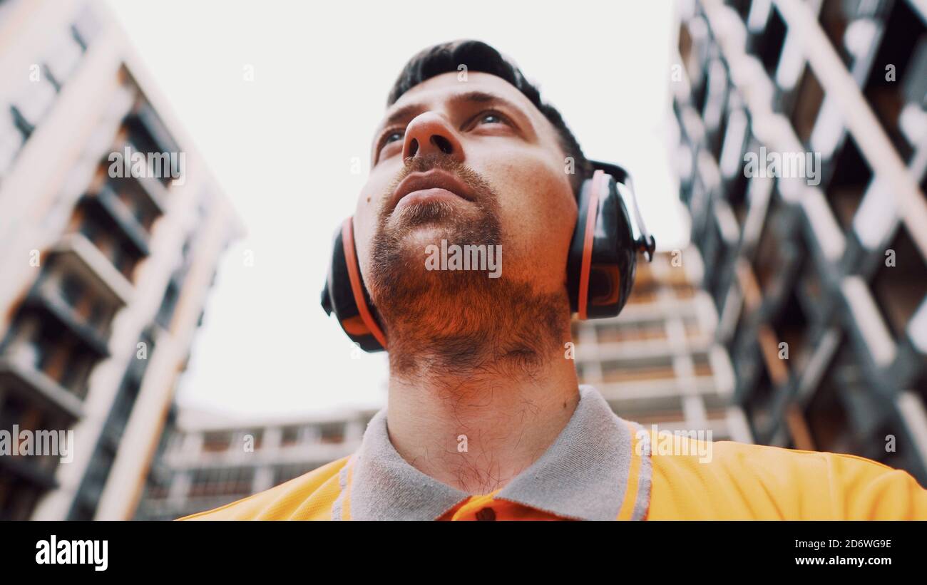 Builder covers his ears, ear muff to protect workers ears. Construction ...