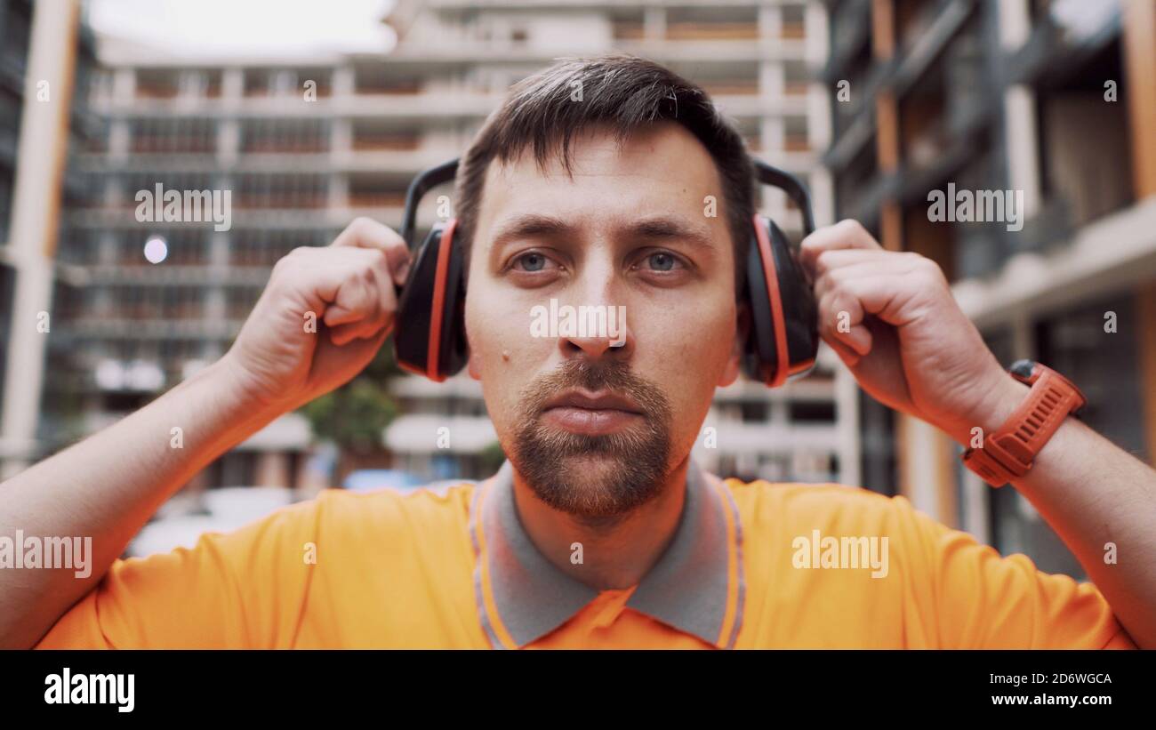Builder covers his ears, ear muff to protect workers ears. Construction ...