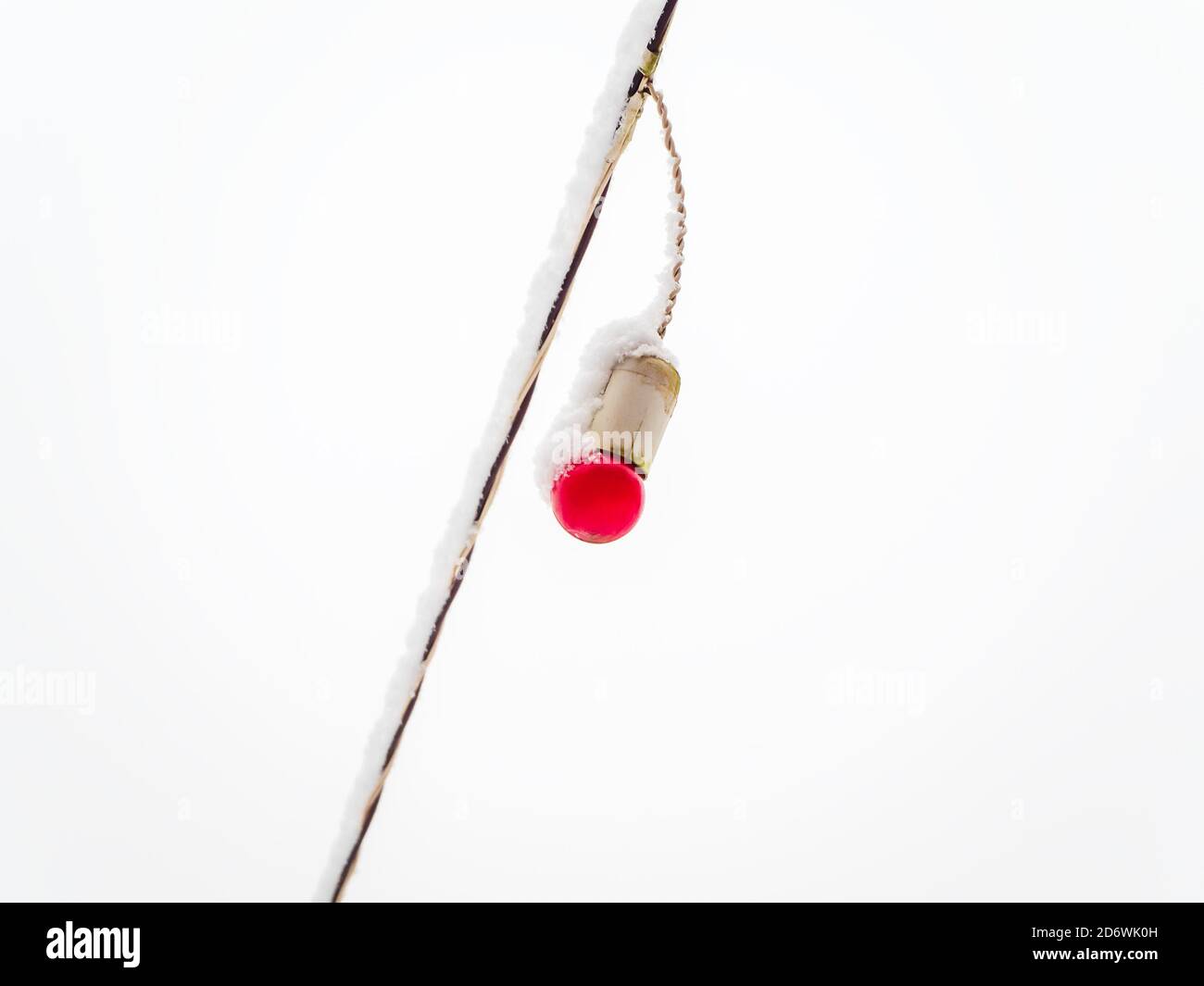 Single red light bulb hanging on cable strewn with snow on isolated ...
