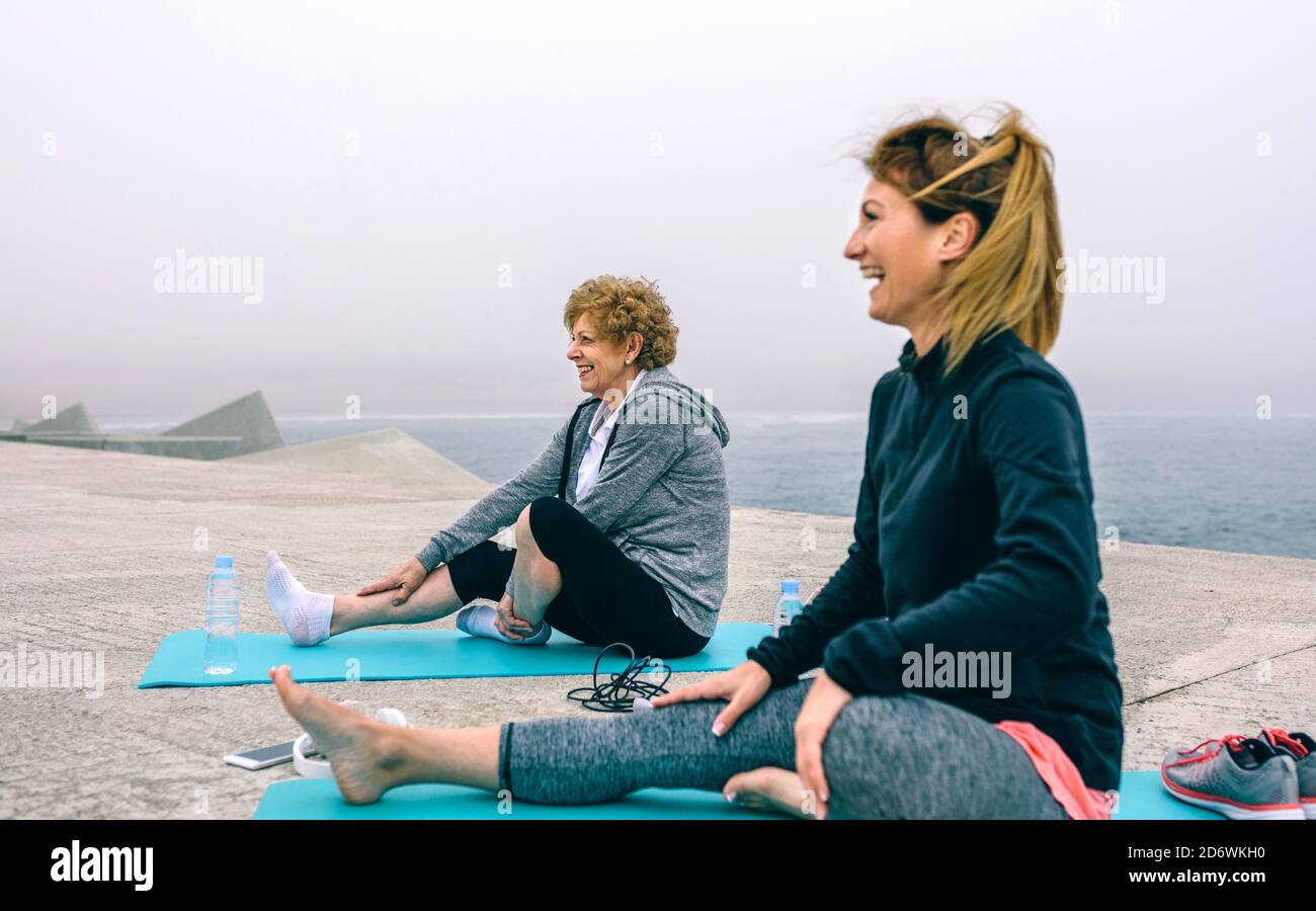 Senior woman stretching legs with female coach Stock Photo - Alamy
