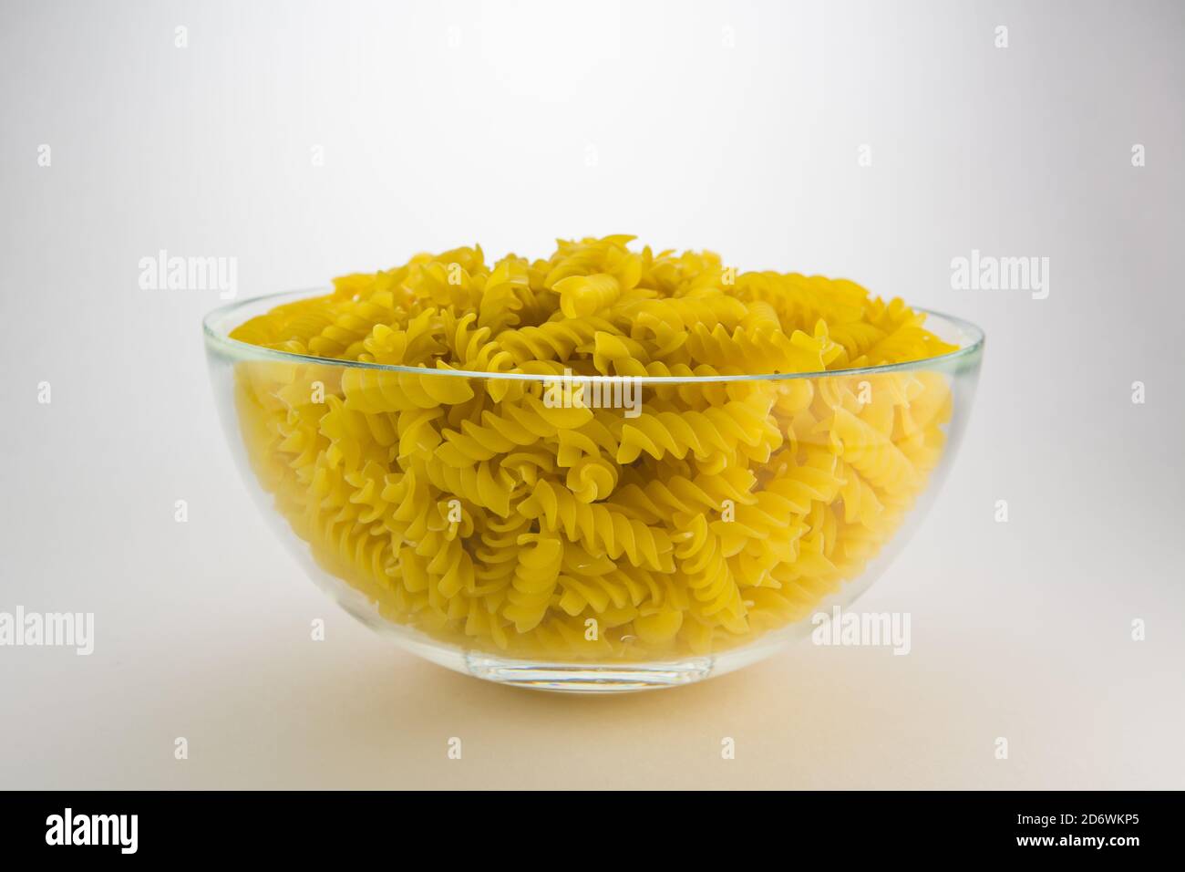 Fusilli in a deep glass plate on a white background Stock Photo - Alamy