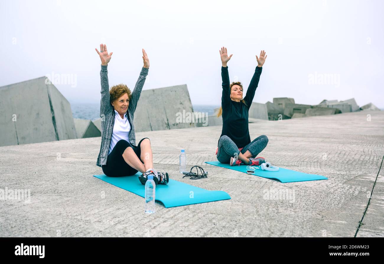 Senior woman stretching arms with coach Stock Photo - Alamy