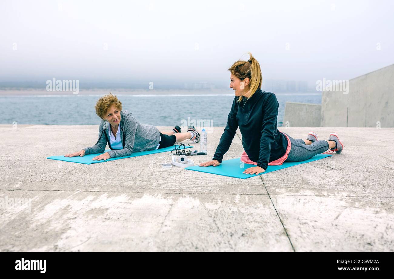 Senior woman with female coach stretching back Stock Photo - Alamy