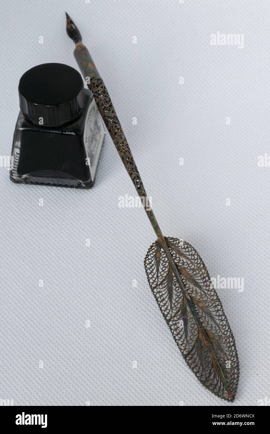 Old ink pen with metal filigreed and ink bottle isolated on white ...