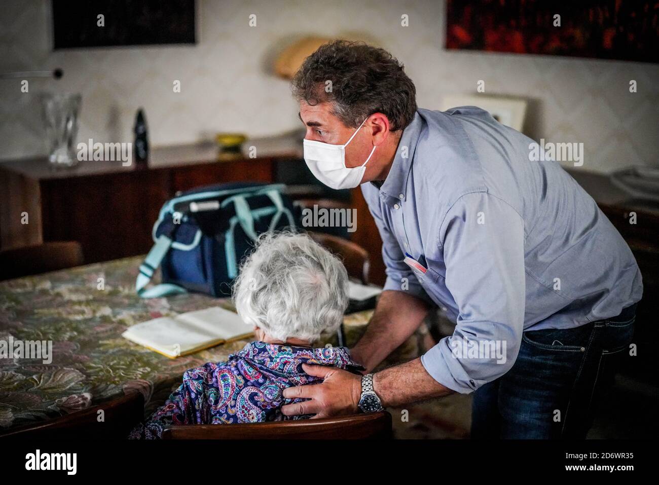 General practitioner wearing a surgery mask, with patient at home ...
