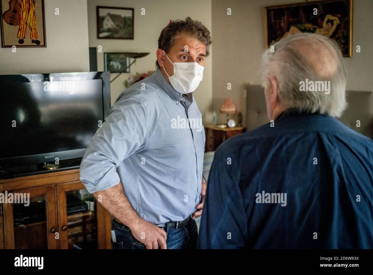 General practitioner wearing a surgery mask, with patient at home ...