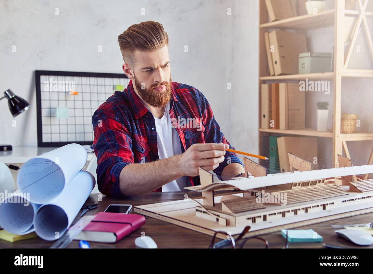 Young male architect holding pencil and working on an architecture house model. Engineering and ...