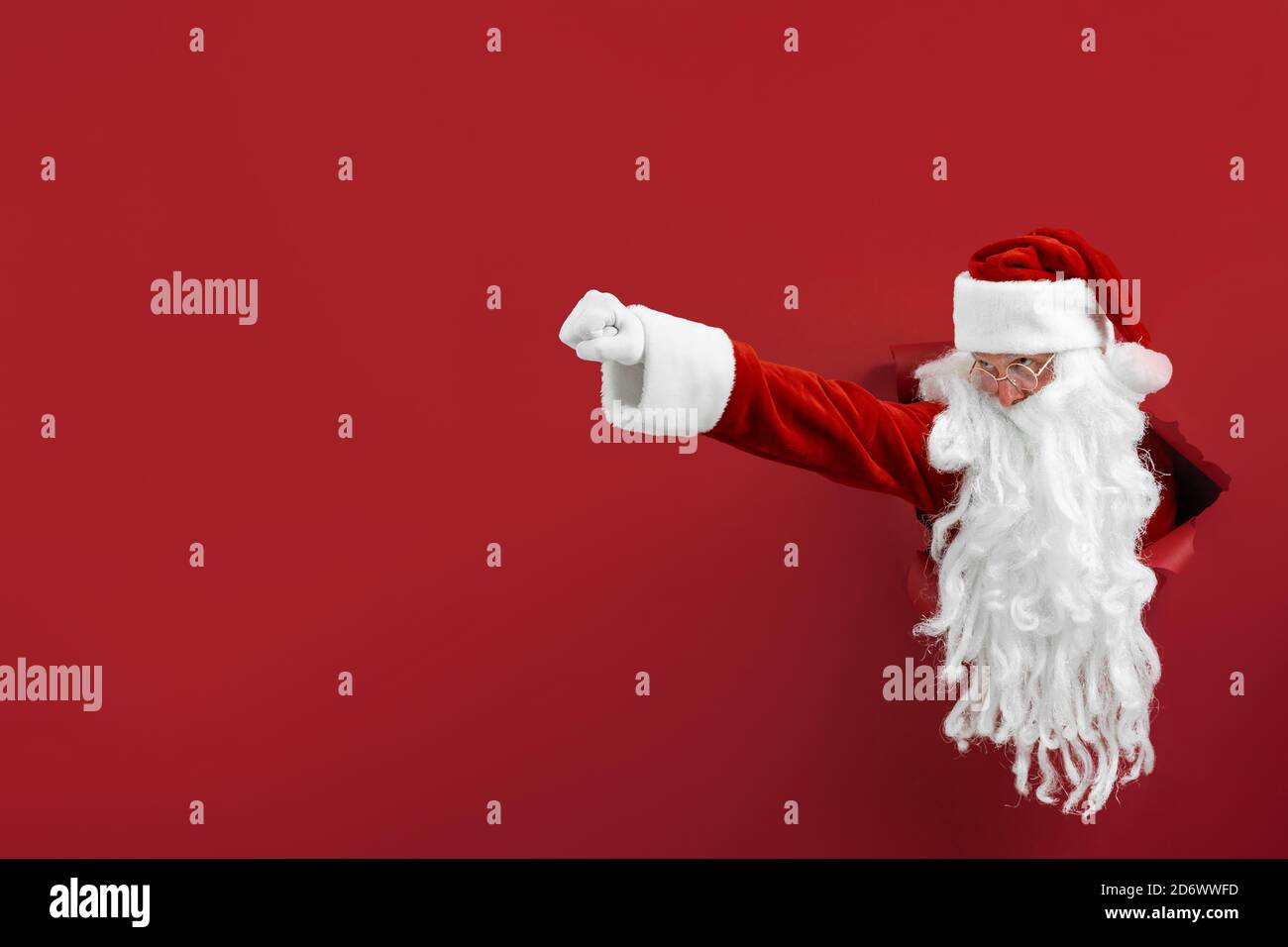 Santa man breaks through hole in paper like super man. Space for text ...