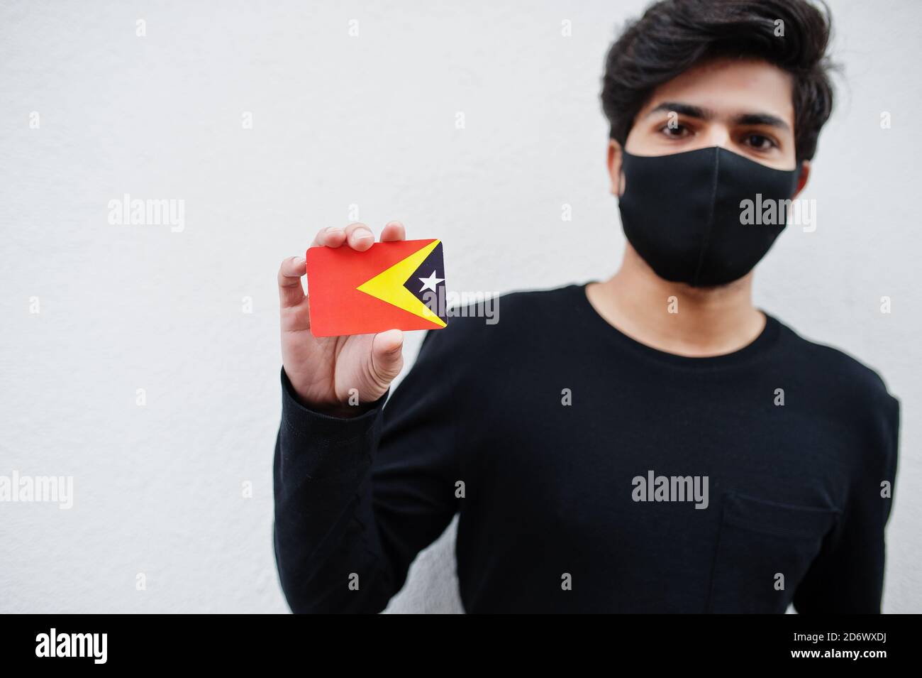 Asian man wear all black with face mask hold East Timor flag in hand ...