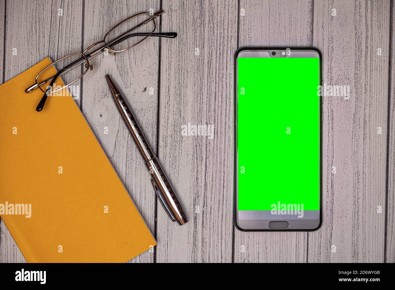 top view of mobile phone with notepad, metal pen and glasses. Cell ...