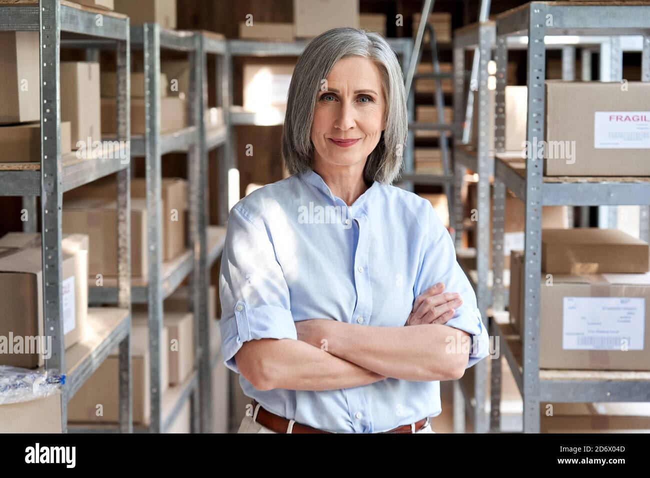 Confident older woman manager standing in delivery shipping warehouse ...