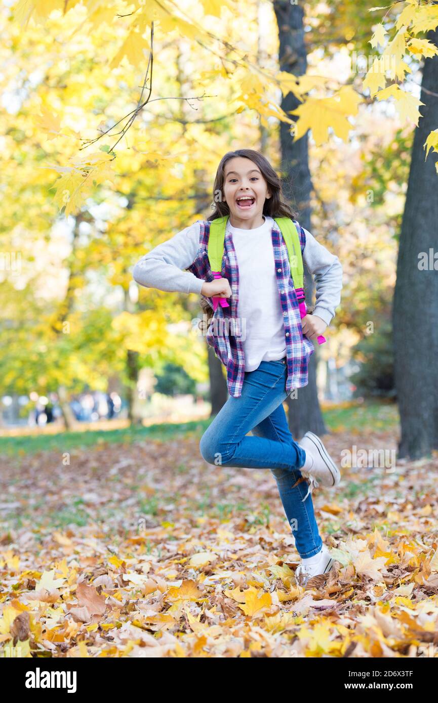 Energetic little kid carry backpack running to school in autumn park ...