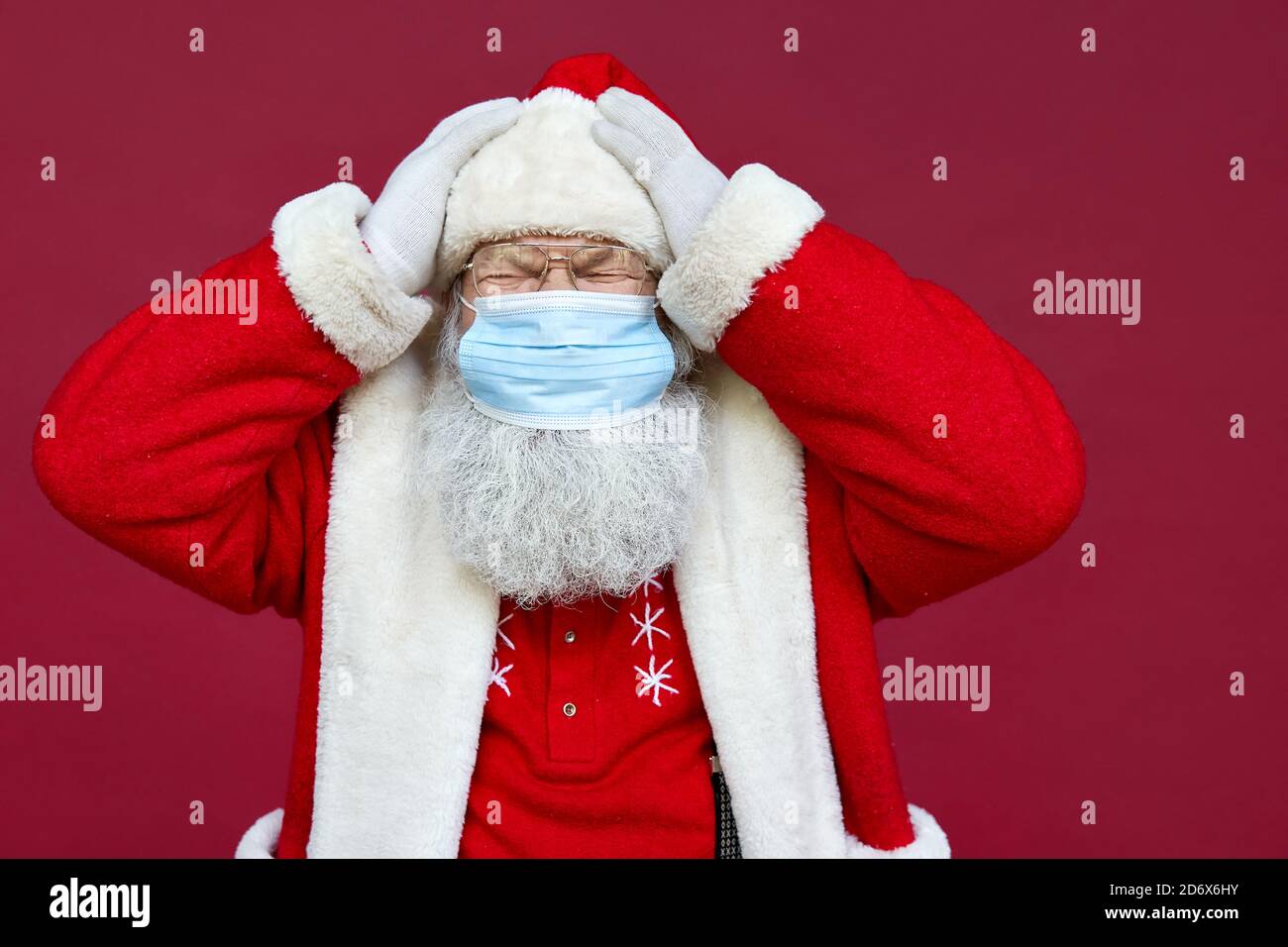 Sick ill Santa Claus wearing face mask feeling headache on red ...