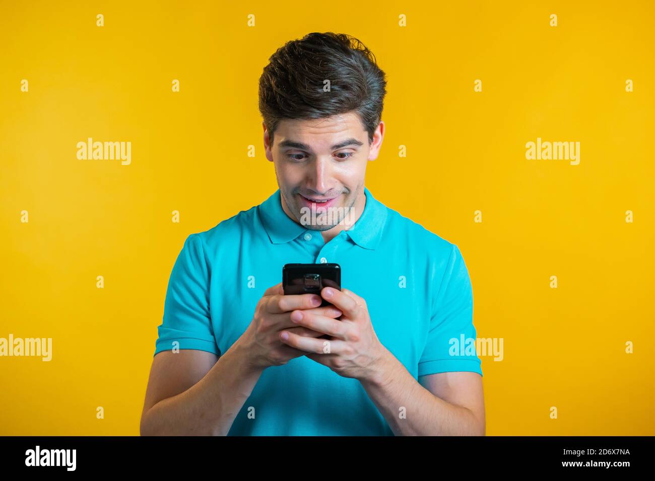 Handsome man receives happy notification on mobile phone. Guy is beside ...