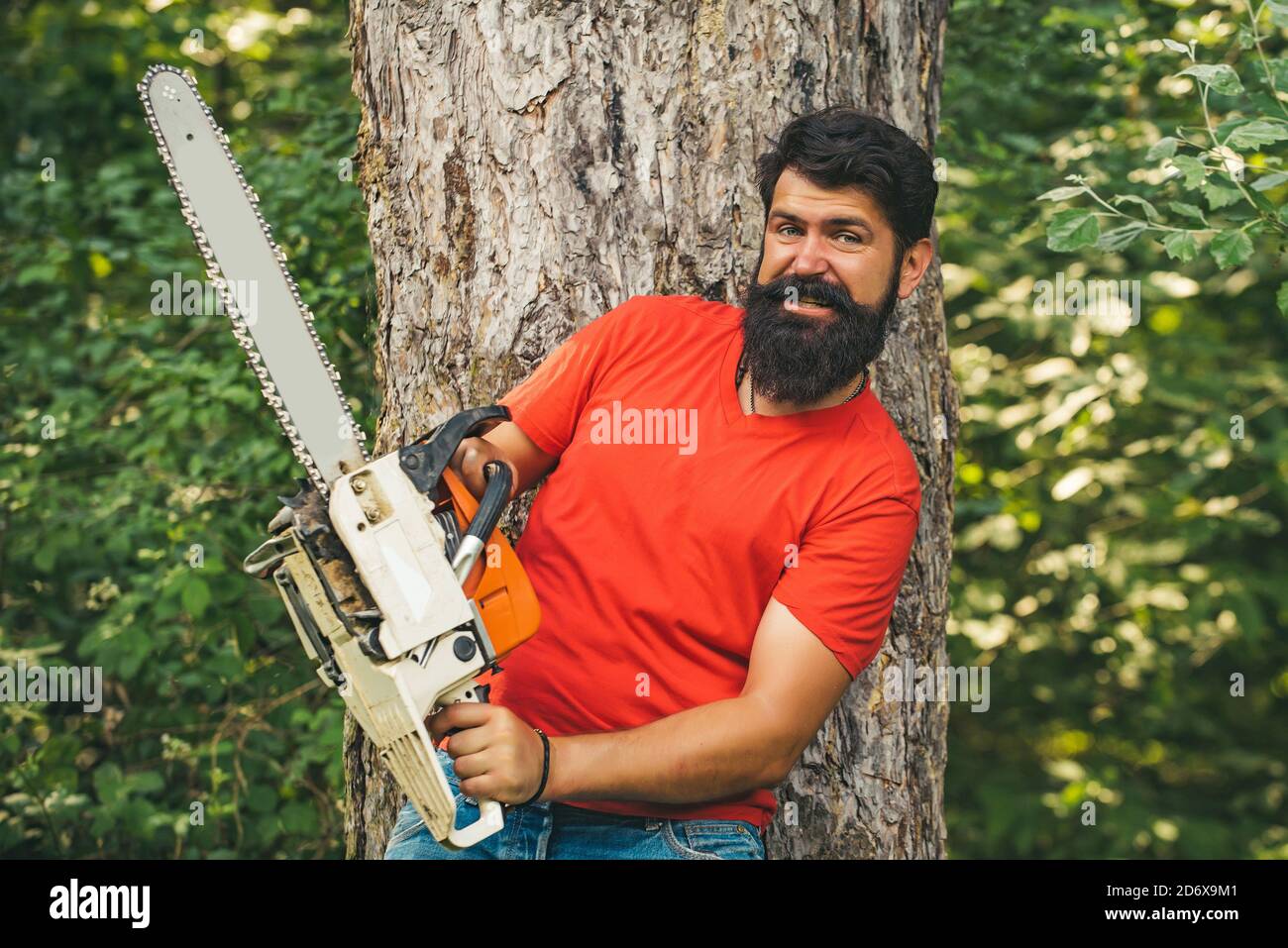 Lumberjack with chainsaw on forest background. Lumberjack holding the ...