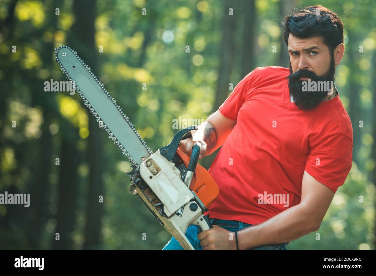 Lumberjack on serious face carries chainsaw. Agriculture and forestry ...