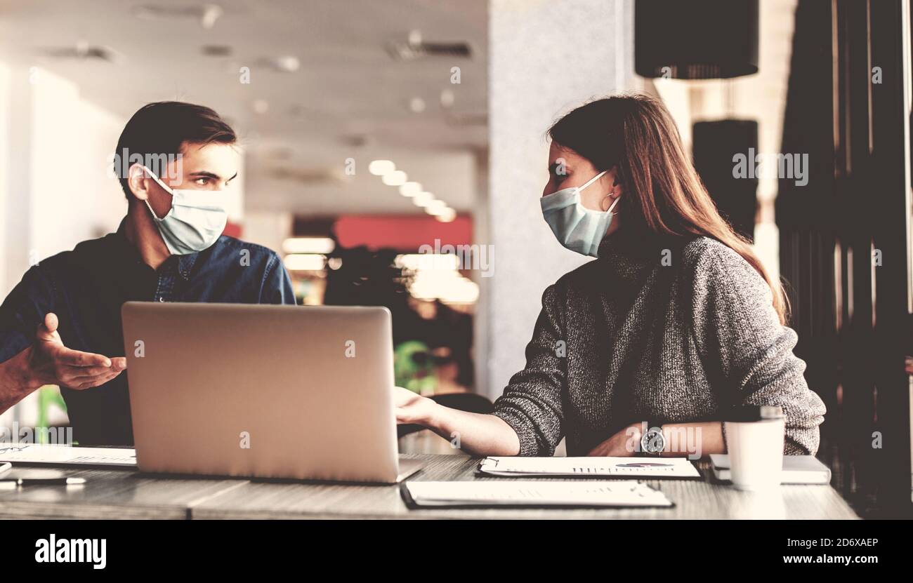 business colleagues in protective masks sitting at the office Desk ...