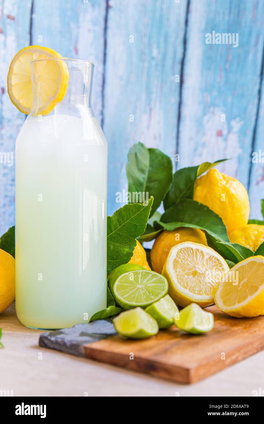 Squeezed lemon juice in a tall glass bottle vase with a lemon on a blue ...