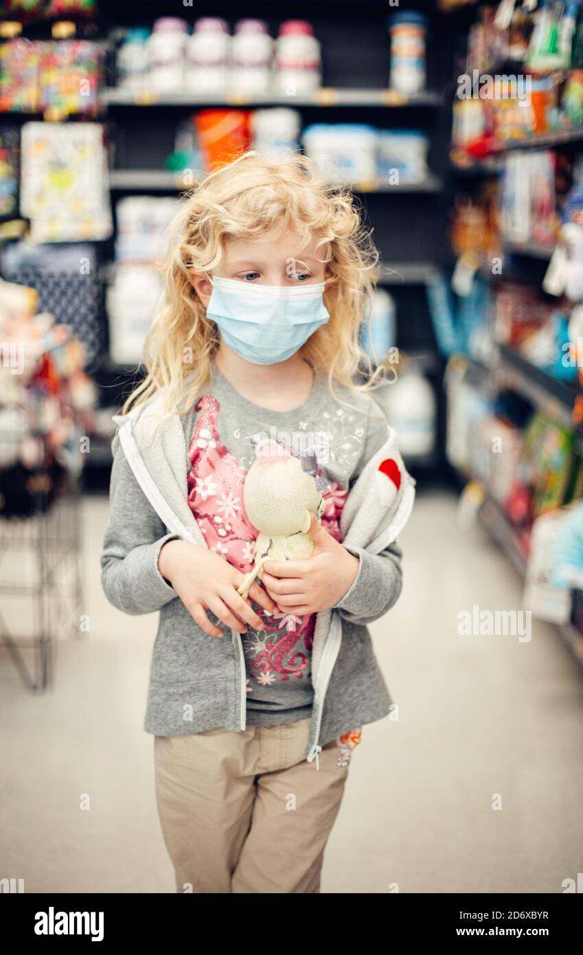 A new normal. Caucasian blonde girl in sanitary face mask shopping at ...