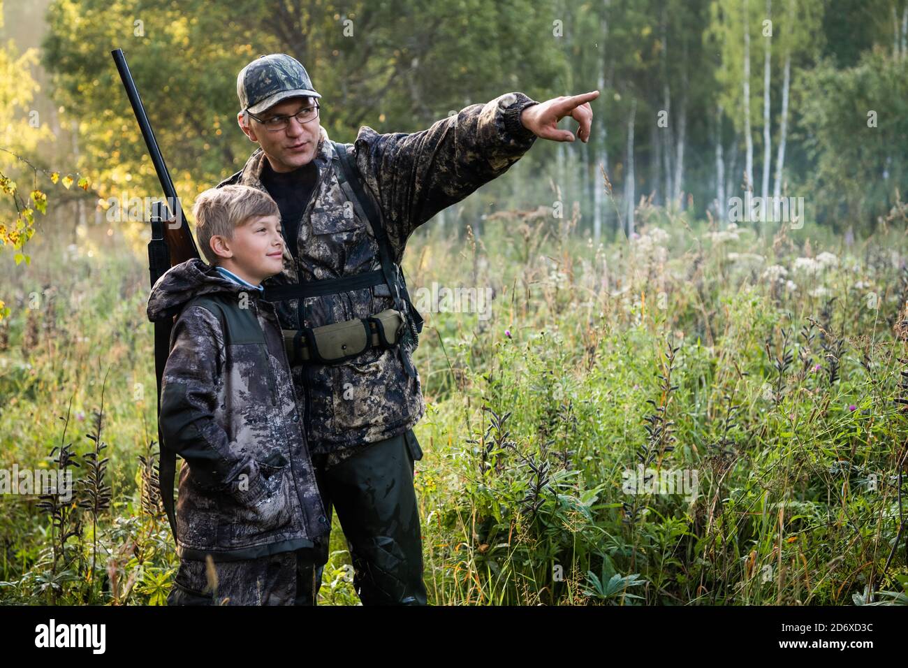 Father's day. Father with gun showing something to son while hunting on ...
