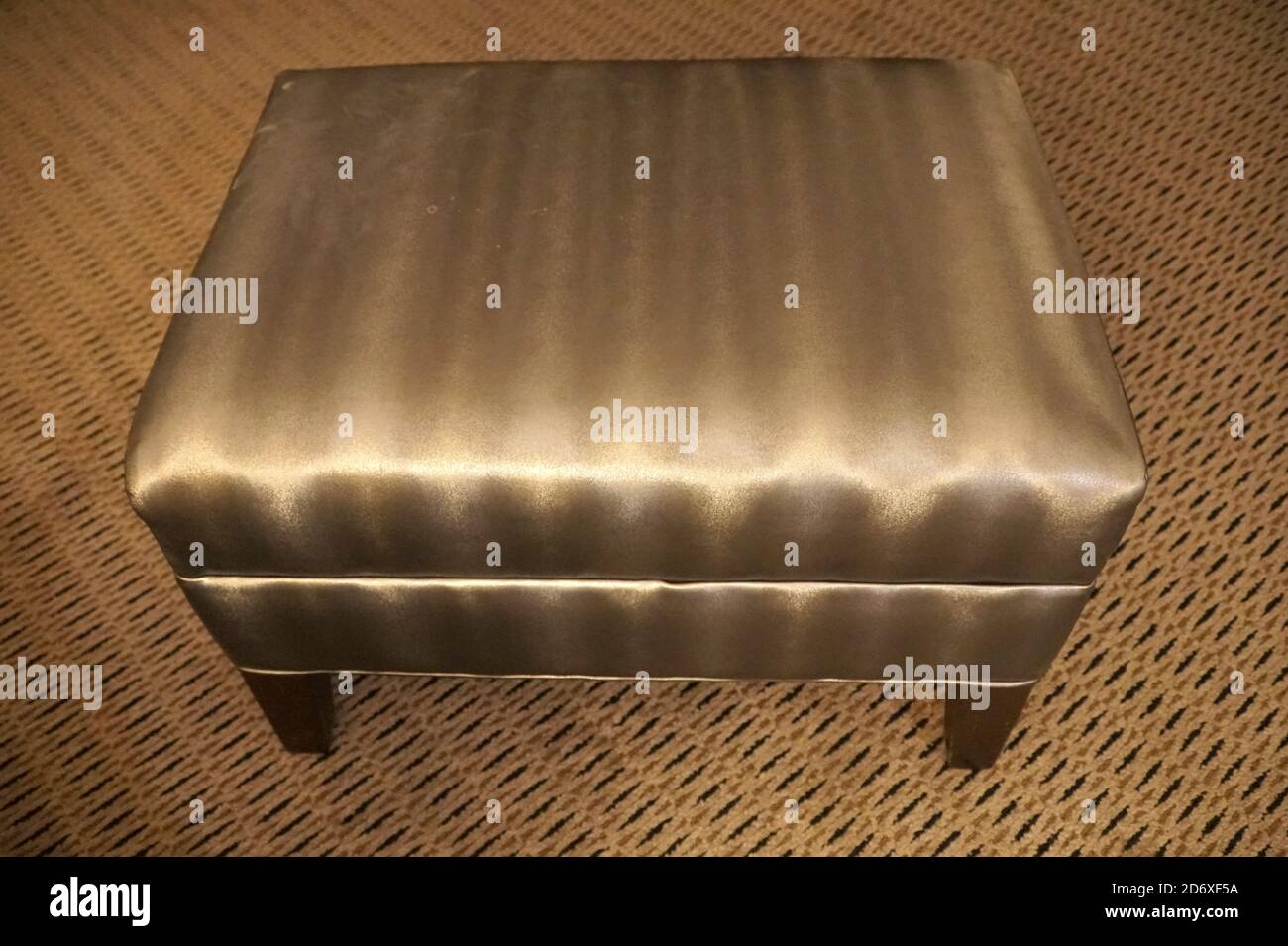A shiny silver color ottoman with wooden legs Stock Photo - Alamy