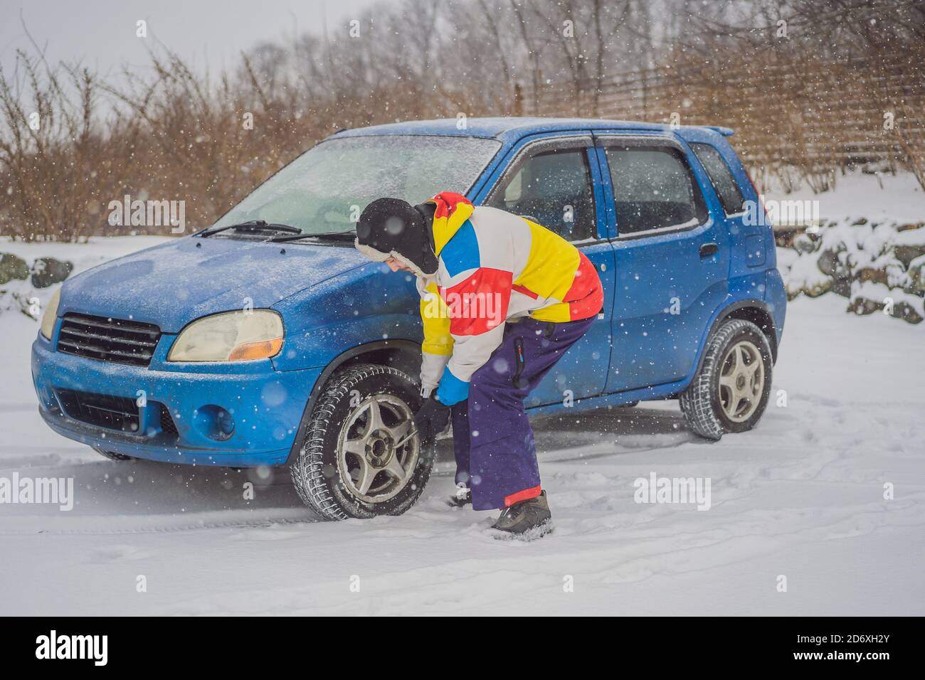 Winter accident on the road. A man changes a wheel during a snowfall ...