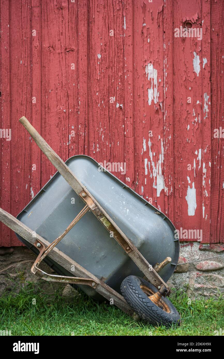 A wheelbarrow leaning on a the outside wall of a barn Stock Photo - Alamy