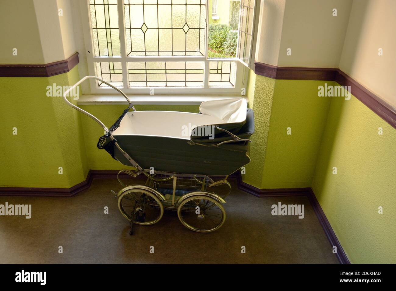 Baby carriage placed beside a glass window with yellow and peach paint ...