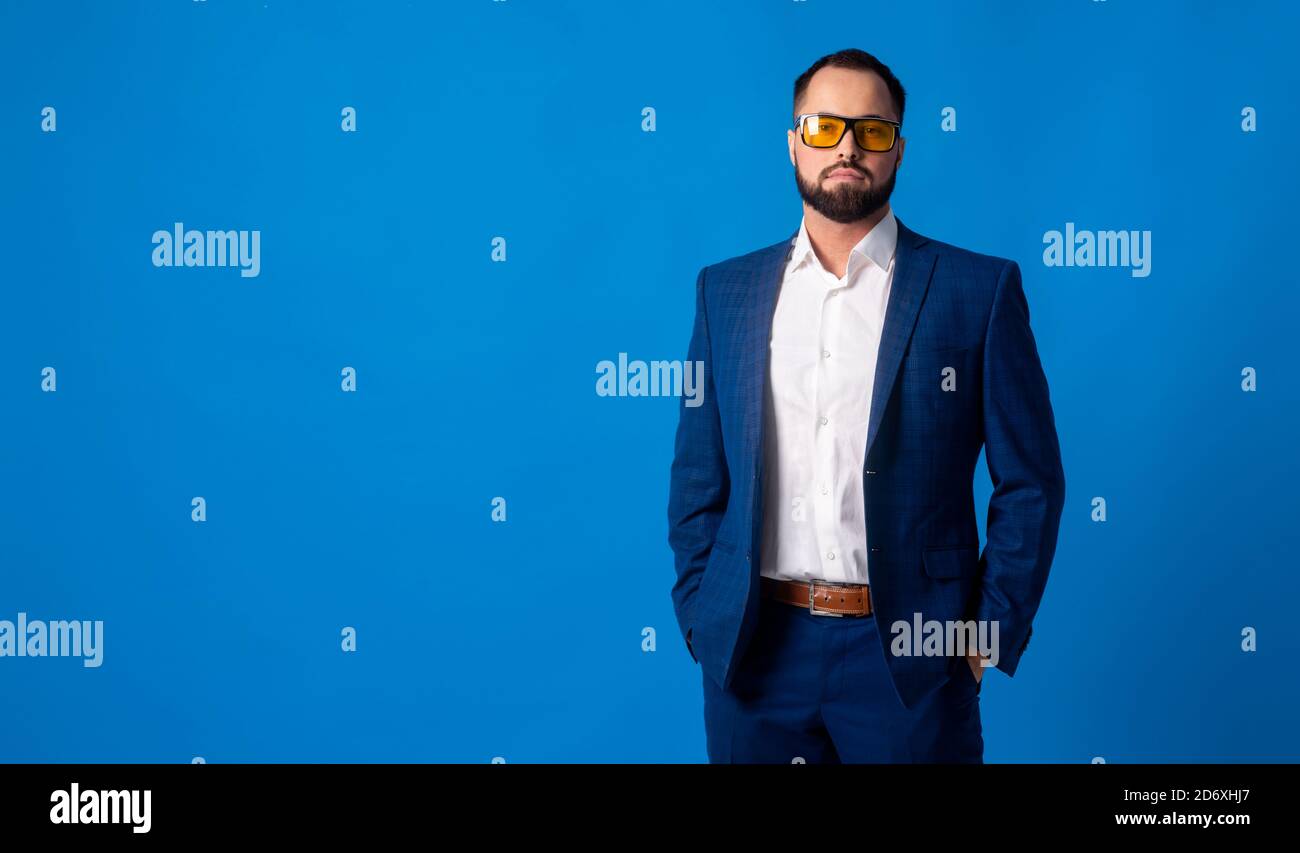 Young man in a classic blue suit on a blue background Stock Photo - Alamy